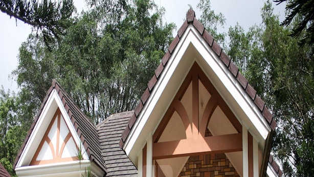 Uma casa com fachada de tijolos, entrada em pedra e pequena varanda com corrimão.