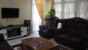 Uma sala de estar com televisão de tela plana, sofá, poltrona e mesa de centro.