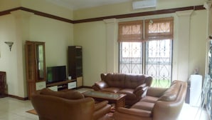 Uma sala de estar com sofá, televisão e armário.