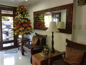 Um quarto com uma escrivaninha de madeira, uma cadeira, um abajur, um espelho e um pinheiro de Natal.