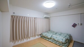 Quarto com cama futon, ventoinha no teto e ar condicionado fixado na parede.