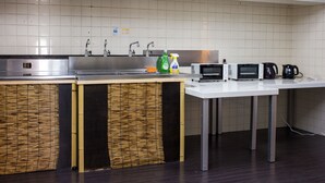 Cozinha moderna com uma pia de aço inoxidável, duas chaleiras elétricas, micro-ondas e máquina de café.