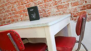 Uma mesa branca com um livro preto intitulado 'indulge' em frente a uma parede de tijolos.