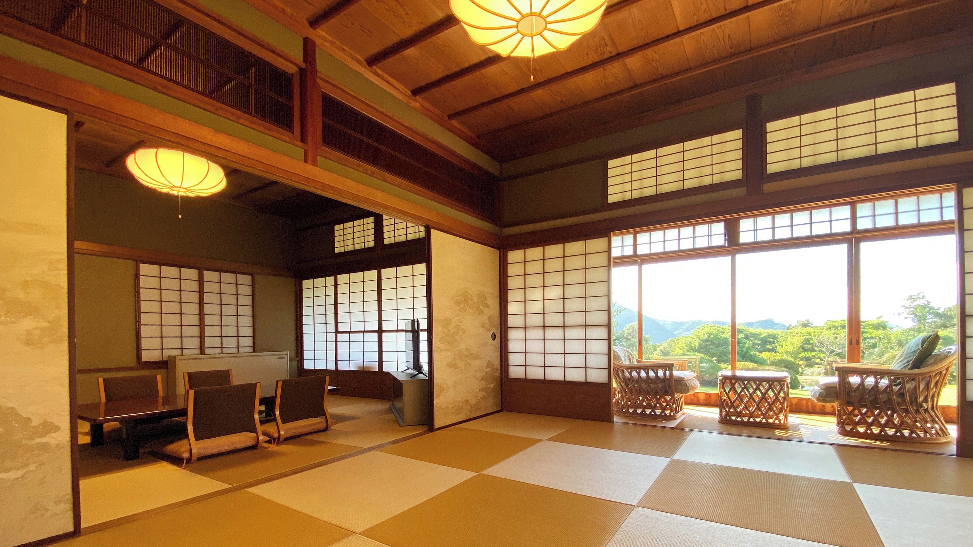 Um quarto japonês tradicional com tatames, portas de correr e vista para as montanhas.