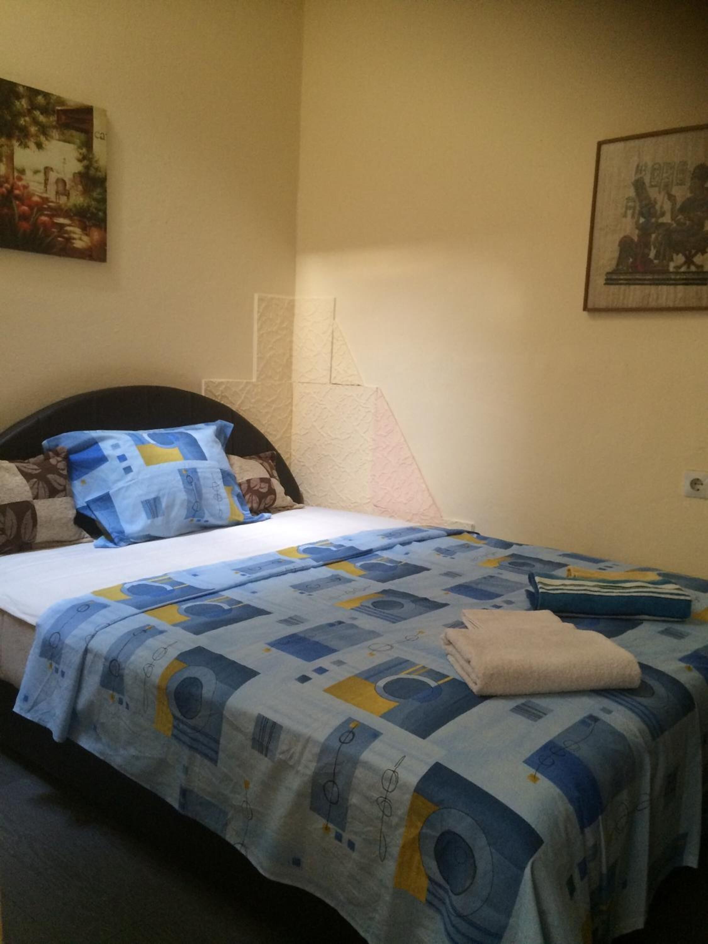 Quarto com cama, travesseiros, cobertor e toalha dobrada.