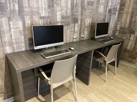 Um espaço de escritório moderno com duas mesas, cada uma equipada com um computador, teclado e rato.