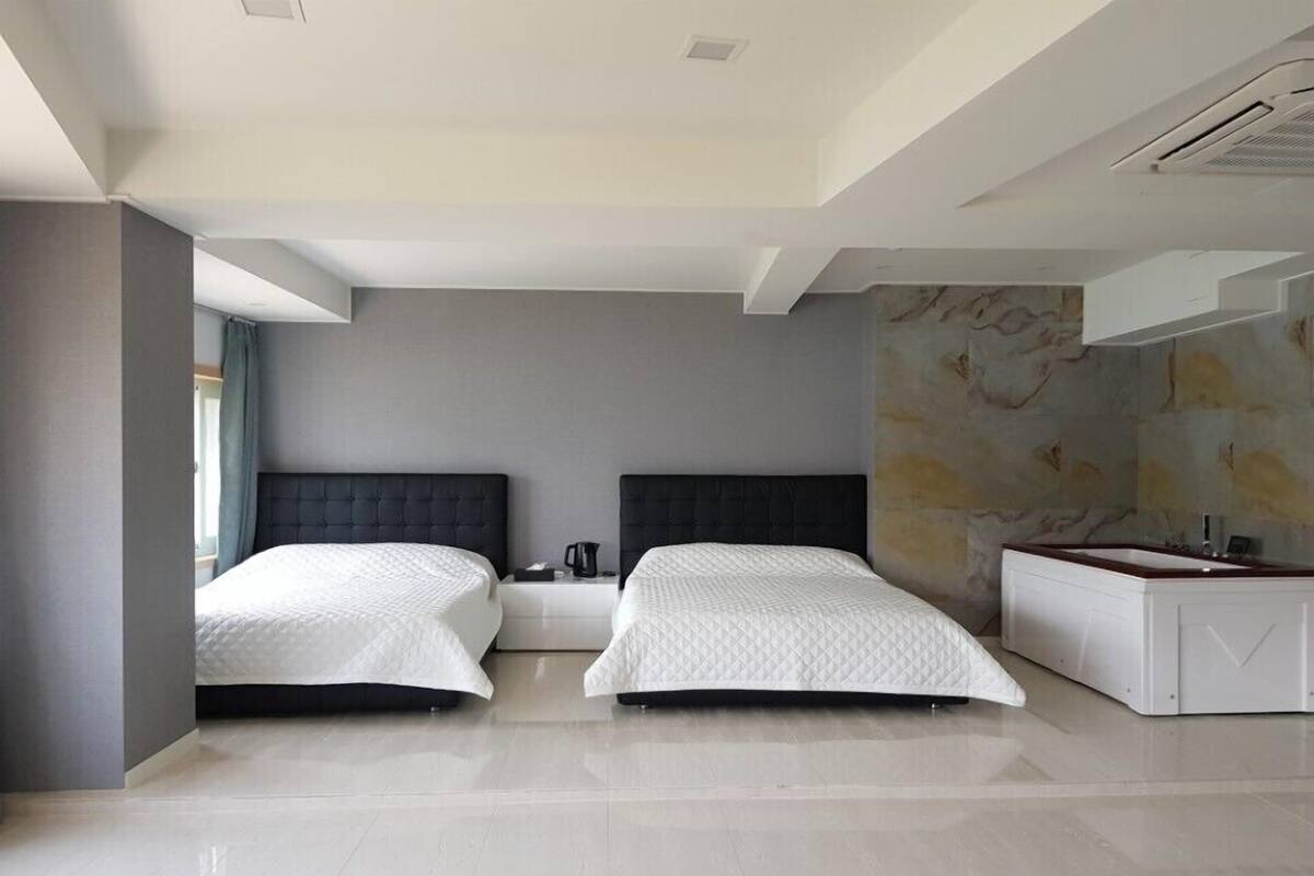 Quarto de hotel moderno com duas camas, um espelho grande e piso de mármore.