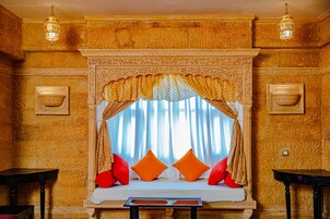 Quarto com cama, cortinas elaboradas e duas lustres.
