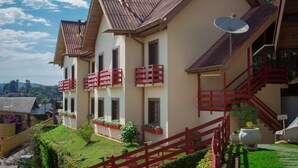 Um edifício de vários andares com telhado inclinado, grades vermelhas e antena parabólica.
