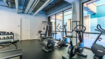 Uma academia com diversos equipamentos de ginástica, incluindo esteiras, elípticos e halteres.