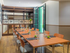 Uma sala de conferências com uma mesa comprida, cadeiras e obras de arte emolduradas nas paredes.