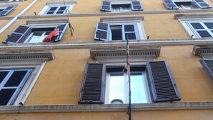 Um edifício com várias janelas, algumas com persianas, e uma porta central com painel de vidro.