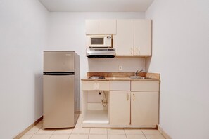 Uma cozinha compacta com geladeira, micro-ondas e armários básicos.