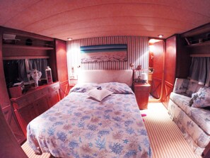 Quarto aconchegante com cama, mesas de cabeceira, cômoda e um espaço para sentar.