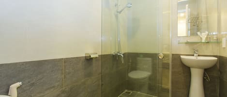 Uma casa de banho moderna com chuveiro em cabine de vidro, lavatório branco e sanita.
