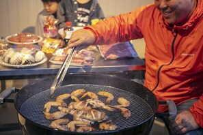 Alguém assando linguiça em uma churrasqueira grande ao ar livre.