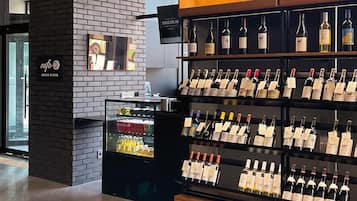 Exposição de vinhos e bebidas em um café, com prateleiras cheias de garrafas de vinho e uma área refrigerada com diversas opções de bebidas.