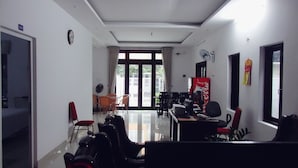 Uma sala de conferências com uma mesa comprida, várias cadeiras, um relógio e uma janela com cortinas.