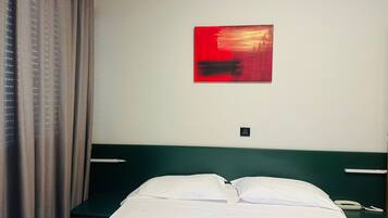 Quarto de hotel com cama, pintura pendurada na parede, telefone e cabeceira verde.