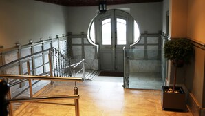 Uma escadaria imponente com piso de mármore e corrimão de ferro forjado.