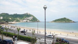 Uma estrada costeira com uma praia e colinas ao fundo.