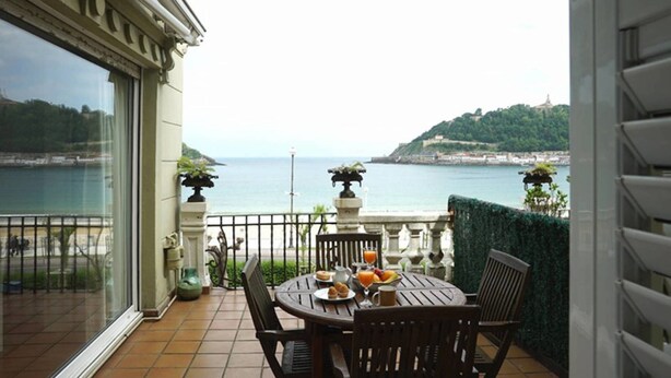 Varanda com mesa posta para café da manhã, com vista para a costa.