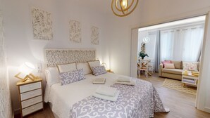 Quarto moderno com cama grande, mesas de cabeceira, escrivaninha e sofá.