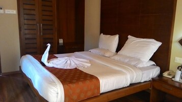 Quarto de hotel com cama de madeira, telefone na mesa de cabeceira e porta com puxador.
