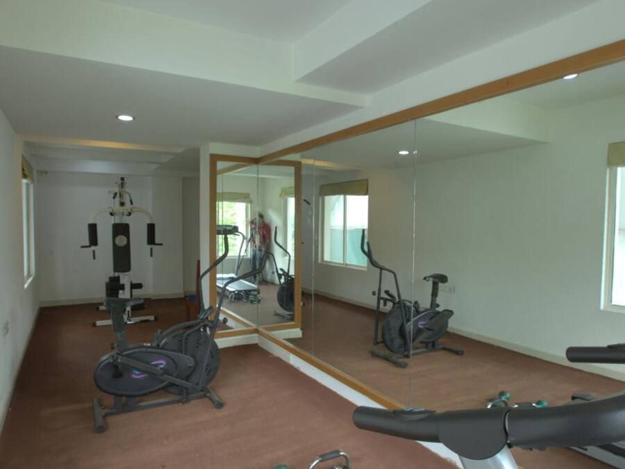 Uma academia com equipamentos de exercício, um espelho e uma esteira.