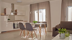 Cozinha moderna com área de jantar, sofá e mesa de centro com plantas.