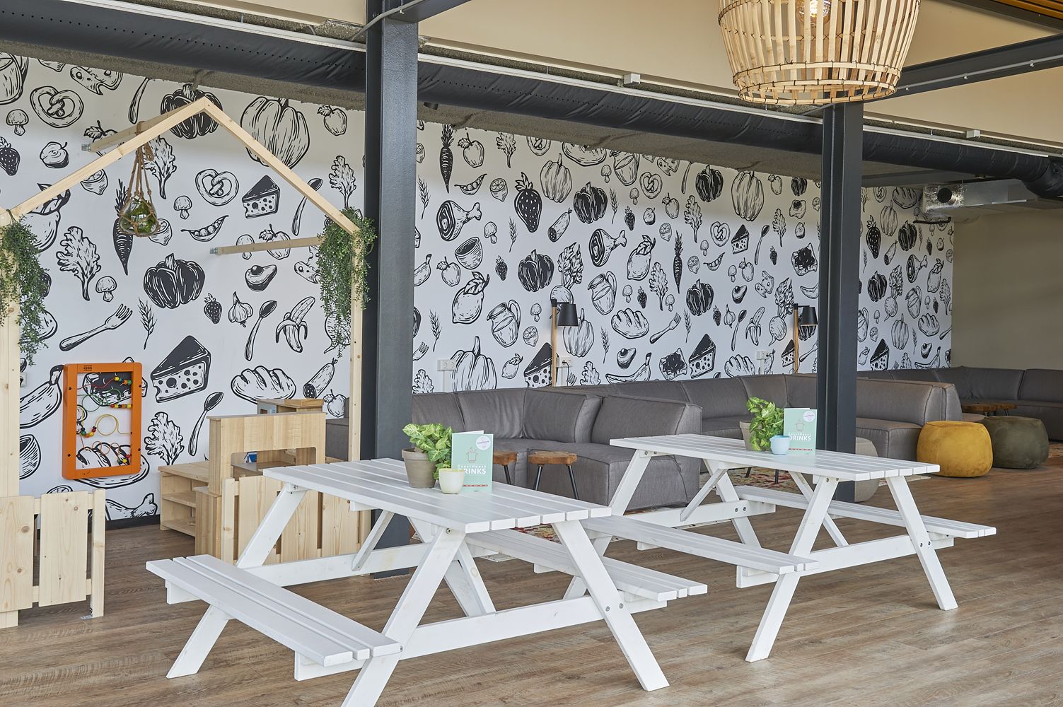 Um interior moderno com mesas brancas, sofás cinzentos e uma parede estampada.