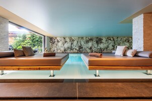 Uma área de spa moderna com duas áreas de estar voltadas para um elemento aquático central.