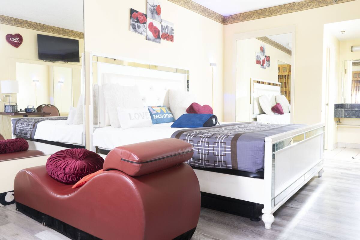Quarto de hotel com cama, sofá, escrivaninha e televisão.