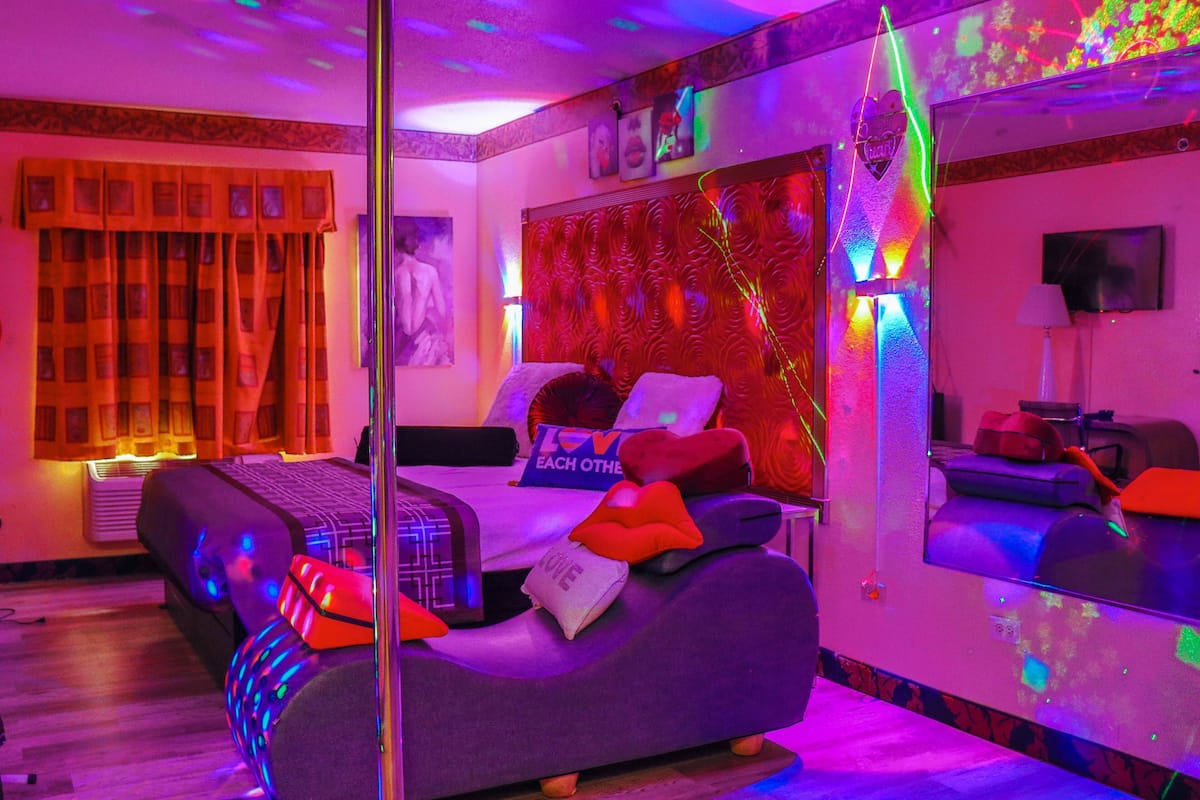 Um quarto moderno com cama, sofá e espelho.