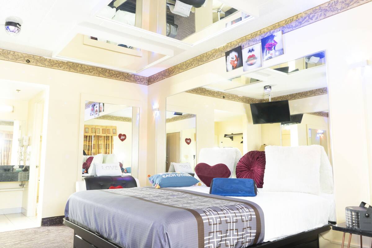 Quarto de hotel com cama grande, televisão de tela plana e teto com iluminação embutida.