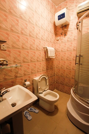 Uma casa de banho com sanita, lavatório e chuveiro.