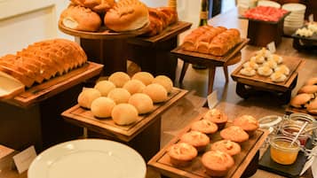 Buffet com diversos produtos de panificação, incluindo pão, pãezinhos e muffins.