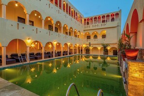 Um hotel com uma piscina interior ampla, várias varandas e iluminação acolhedora.