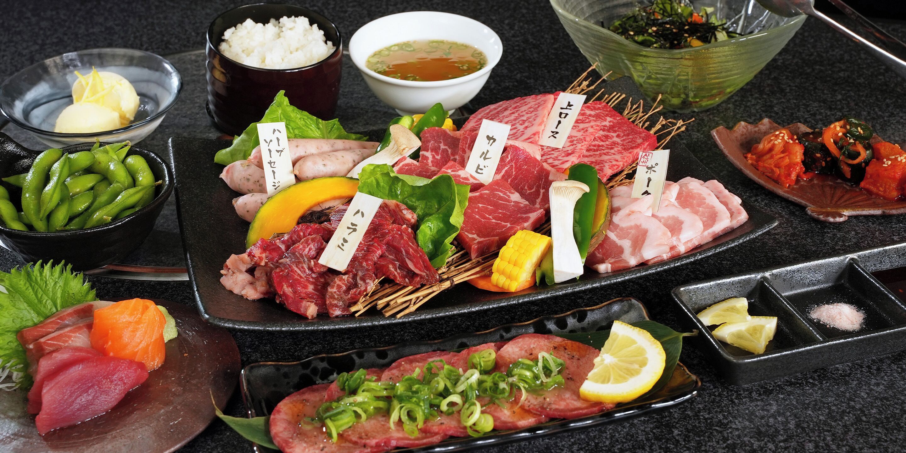 Diversos tipos de carnes cruas e vegetais dispostos em uma bandeja, com etiquetas identificando cada item.