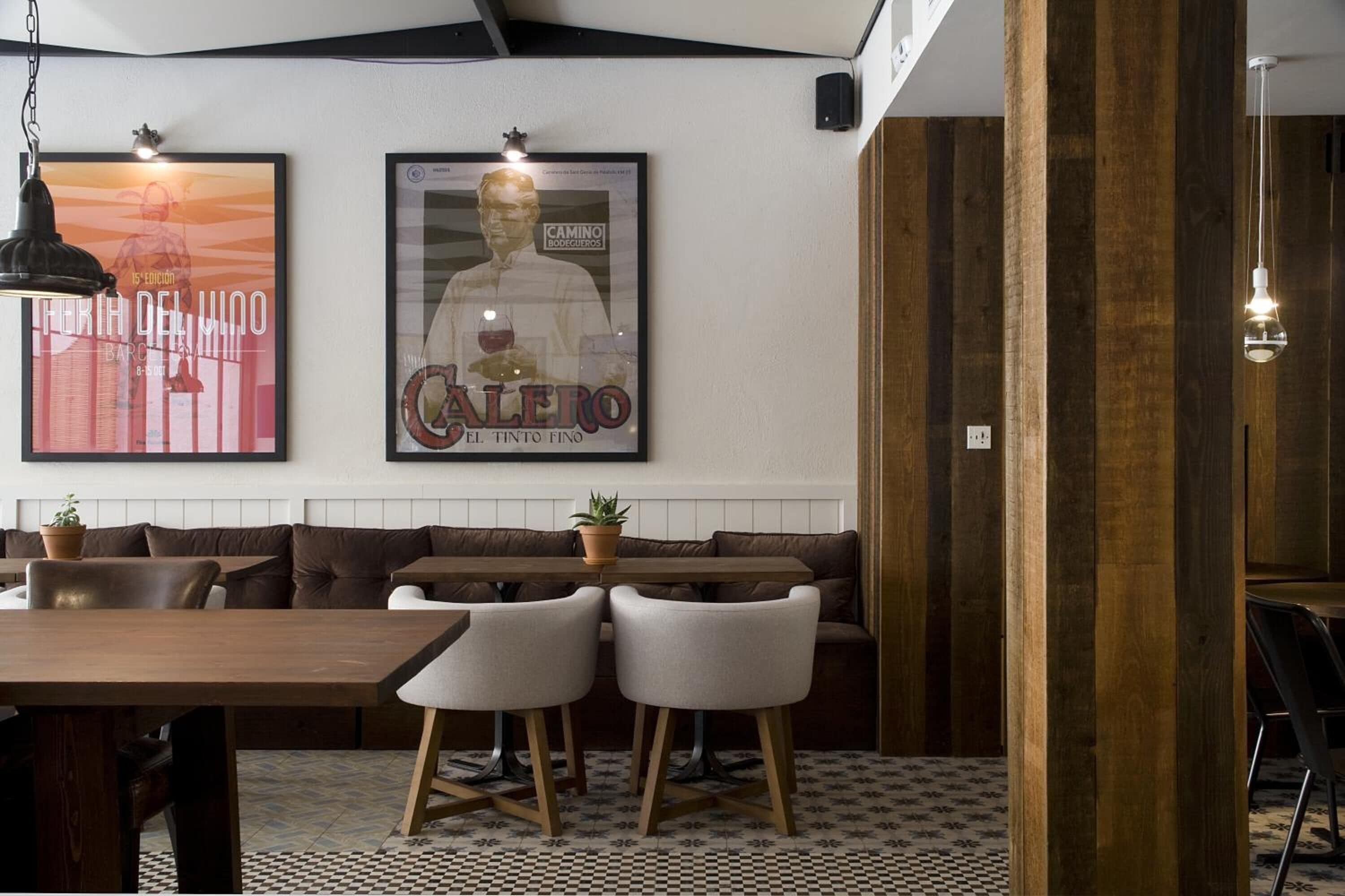 Um restaurante com interior em madeira, chão xadrez e dois cartazes emoldurados na parede.
