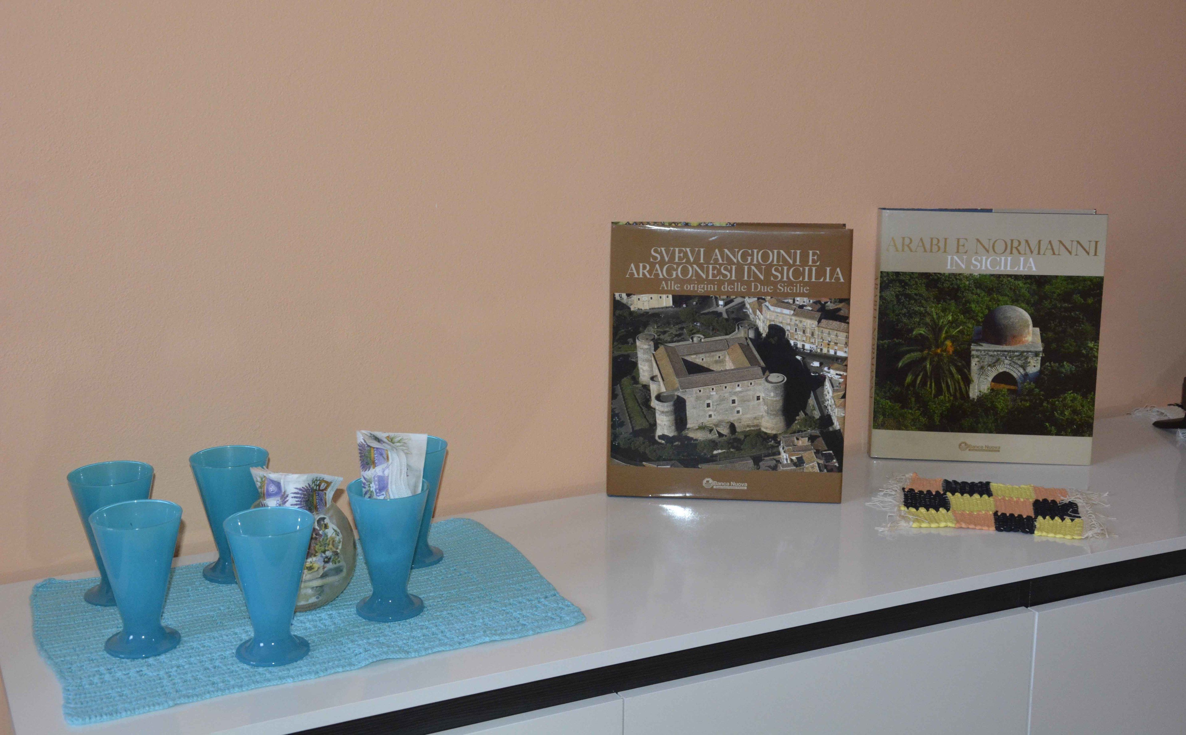 Uma mesa com dois livros, um tecido azul e copos de vidro azuis.
