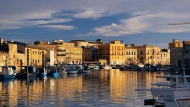 Uma marina com barcos atracados ao longo da orla, rodeada por edifícios com estilo arquitetônico uniforme.