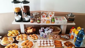 Mesa de buffet com diversos alimentos, incluindo sanduíches, doces e sobremesas.