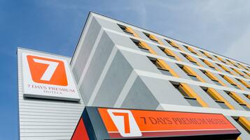 Um hotel com um letreiro chamativo com o número '7' e o texto '7 DAYS PREMIUM HOTEL', indicando uma estadia premium de 7 dias.