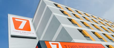 Um hotel com um letreiro chamativo com o número '7' e o texto '7 DAYS PREMIUM HOTEL', indicando uma estadia premium de 7 dias.