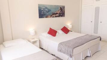 Quarto de hotel com duas camas, um quadro na parede e um guarda-roupa.
