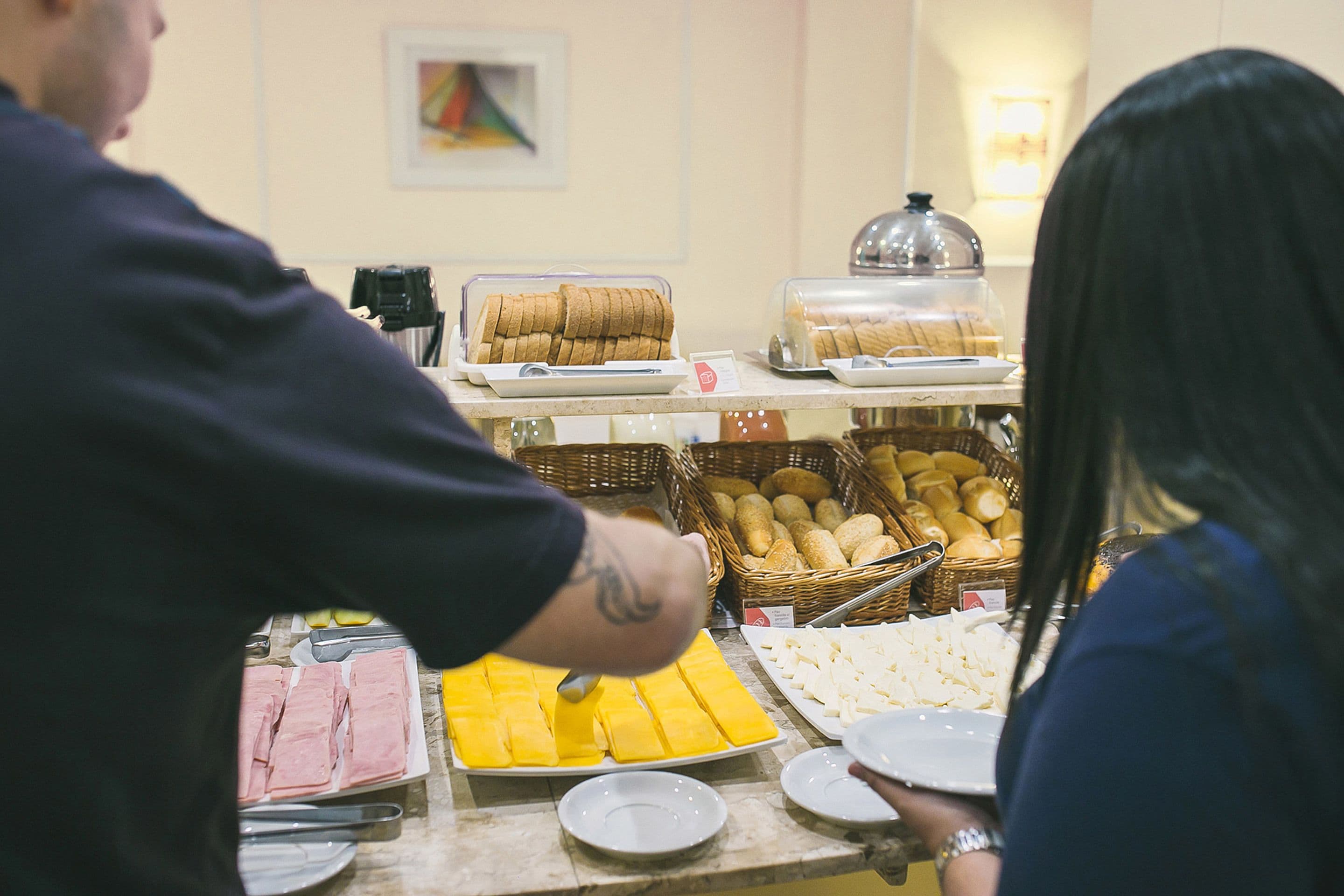 Buffet com diversos alimentos, incluindo pão, queijo e carnes.
