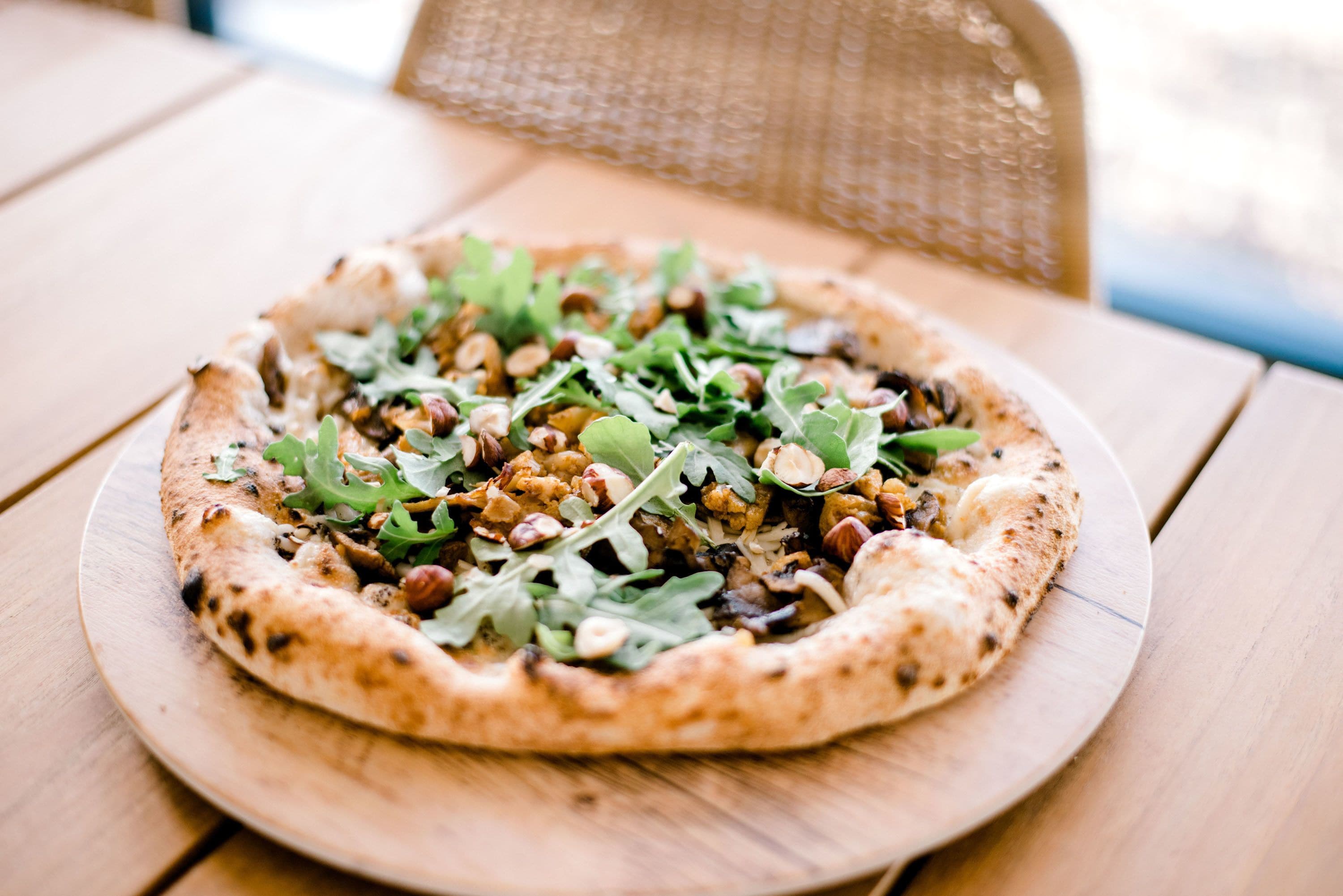 Uma pizza em uma tábua de madeira sobre uma mesa.