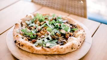 Uma pizza em uma tábua de madeira sobre uma mesa.