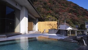 Um edifício moderno com piscina, deck de madeira e vista para uma encosta.